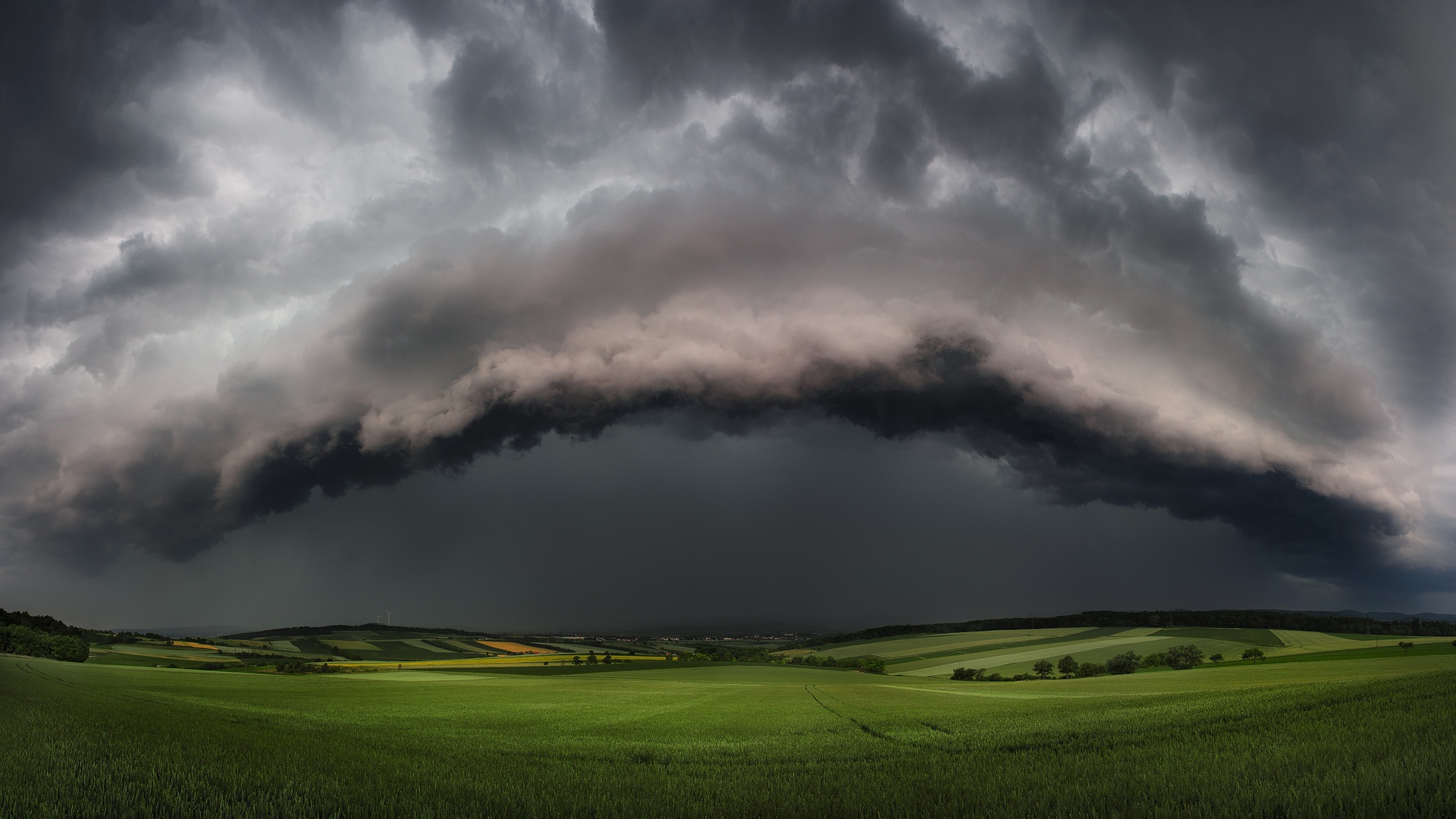 HD Stormscape: Majestic Clouds Over Lush Green Landscape